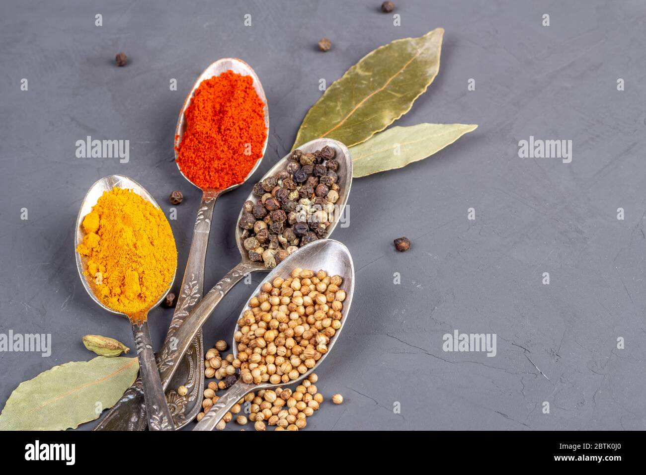 Dry spices of different colors in teaspoons and bay leaf. Top view ...