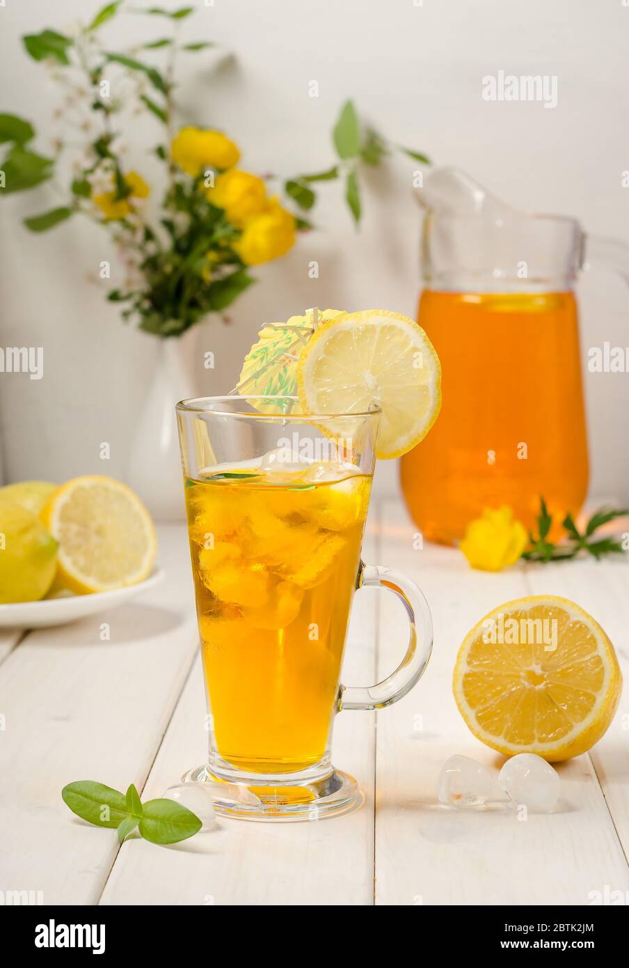 Lemonade in a tall glass with ice, a slice of lemon and mint on a white ...