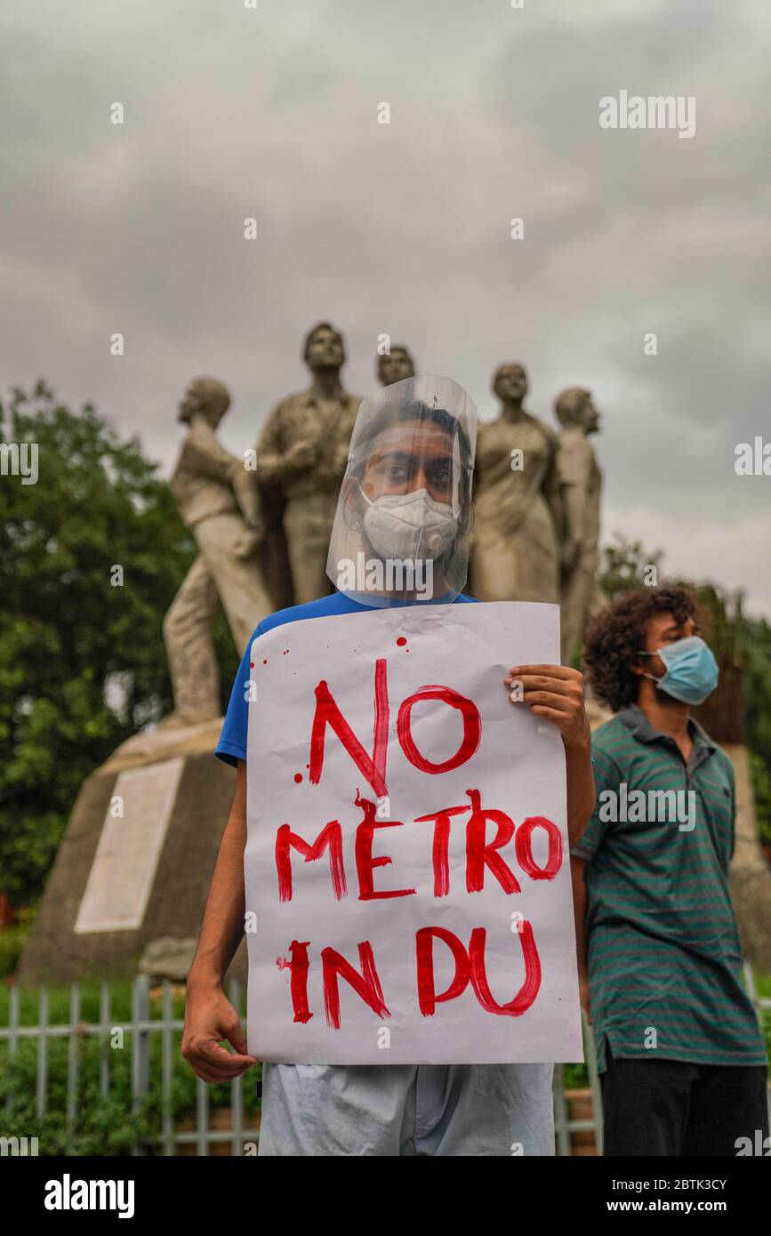 A demonstrator holding a placard while wearing a face shield and a face ...