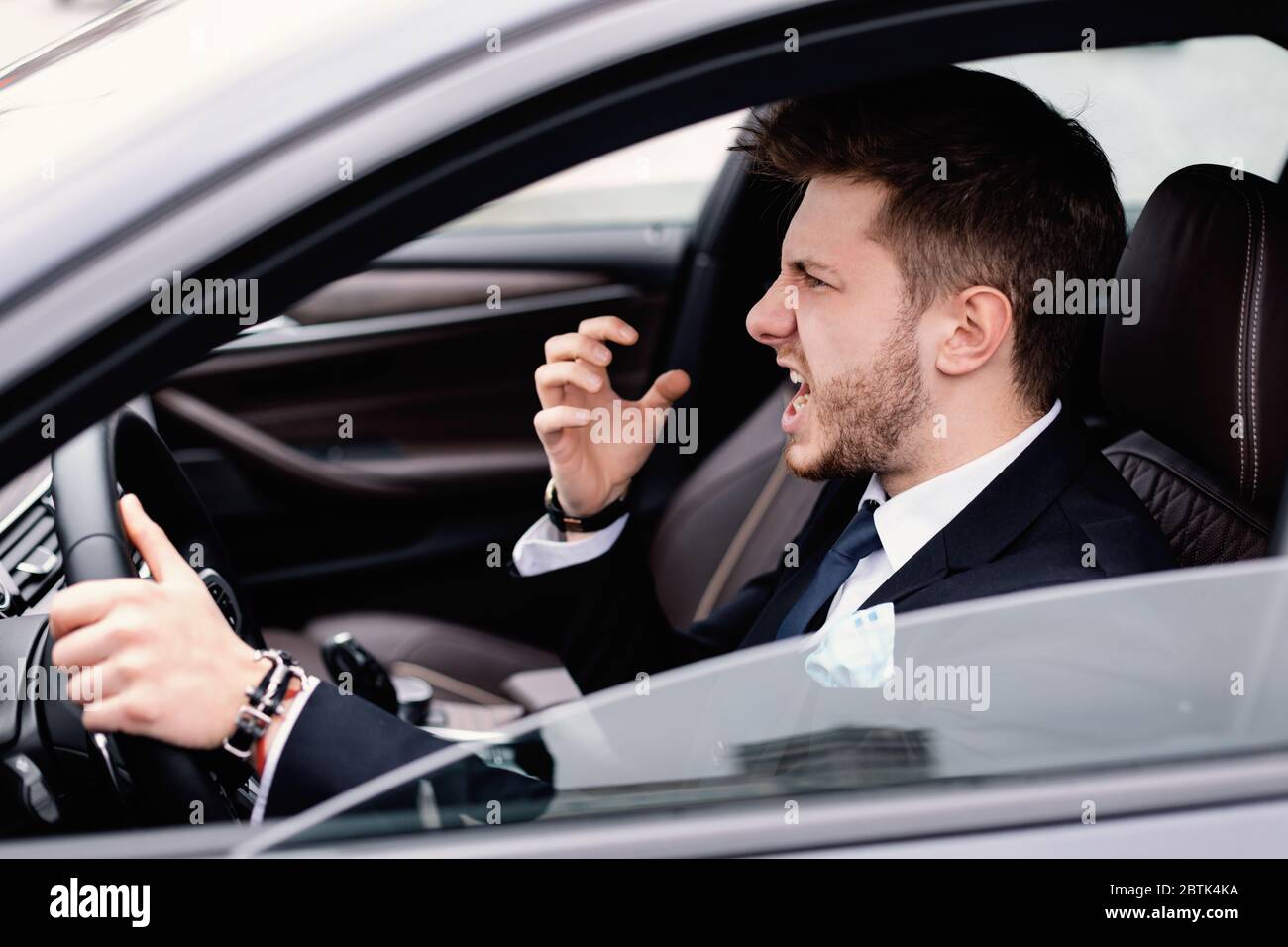 Aggressive man in suit driving car in urban city, shouting and angrily ...