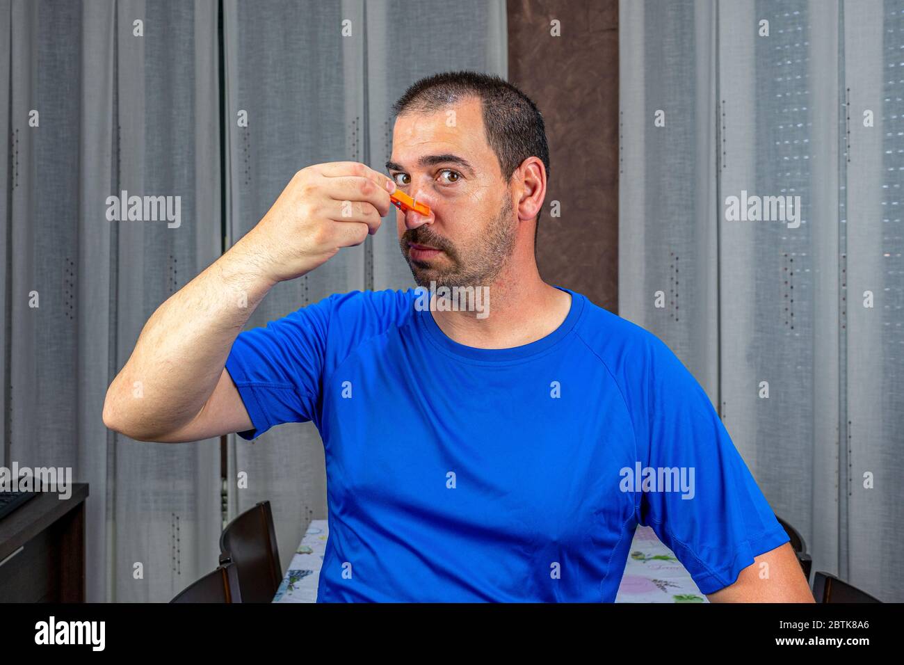 Man with a beard and short hair in a blue shirt with a clothespin on ...