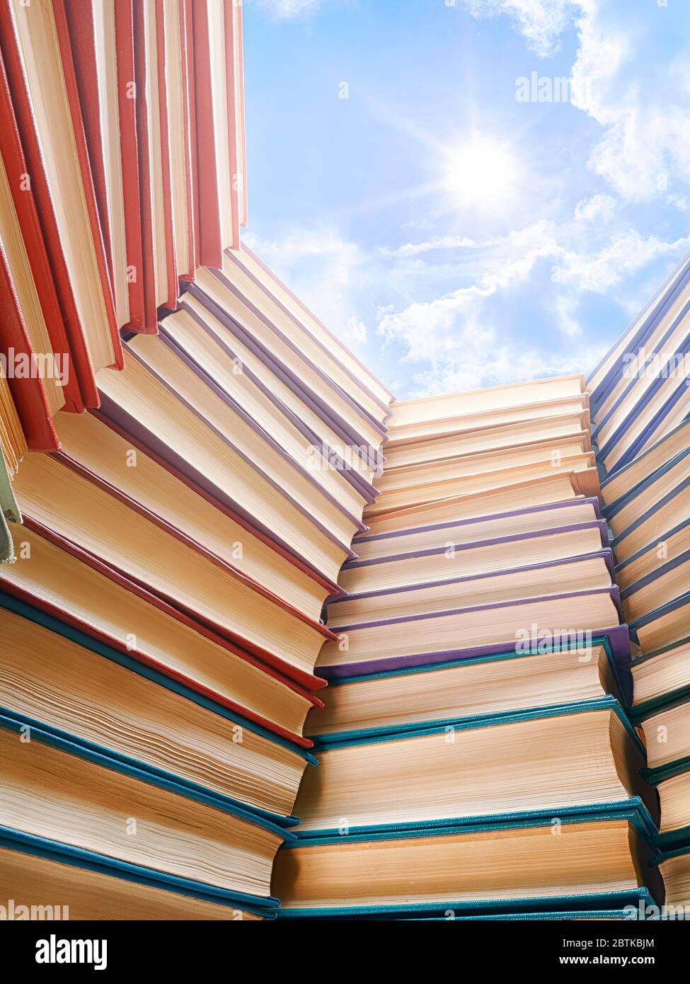 Large books pile and bright sky and sun above it. Education, science ...