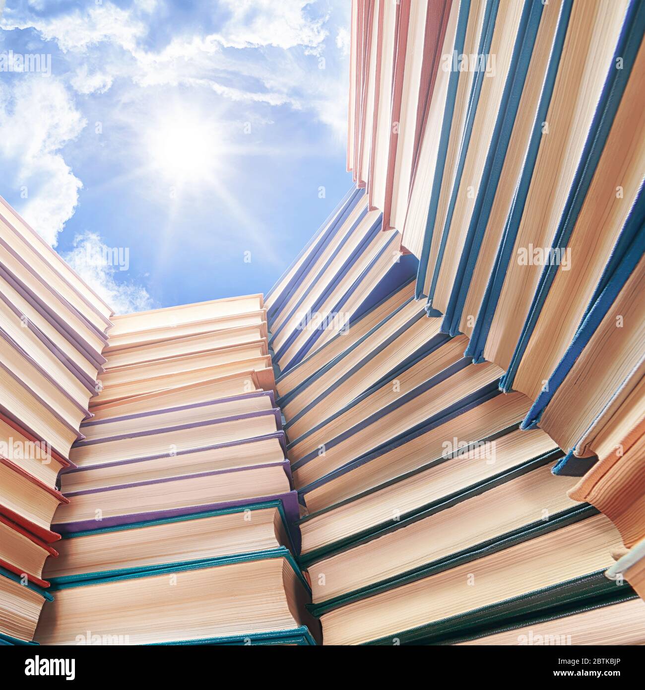 Large books pile and bright sky and sun above it. Education, science ...