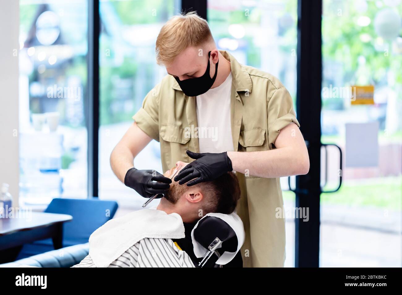 Men's haircut in a barbershop. Client and barber in anti-virus masks ...