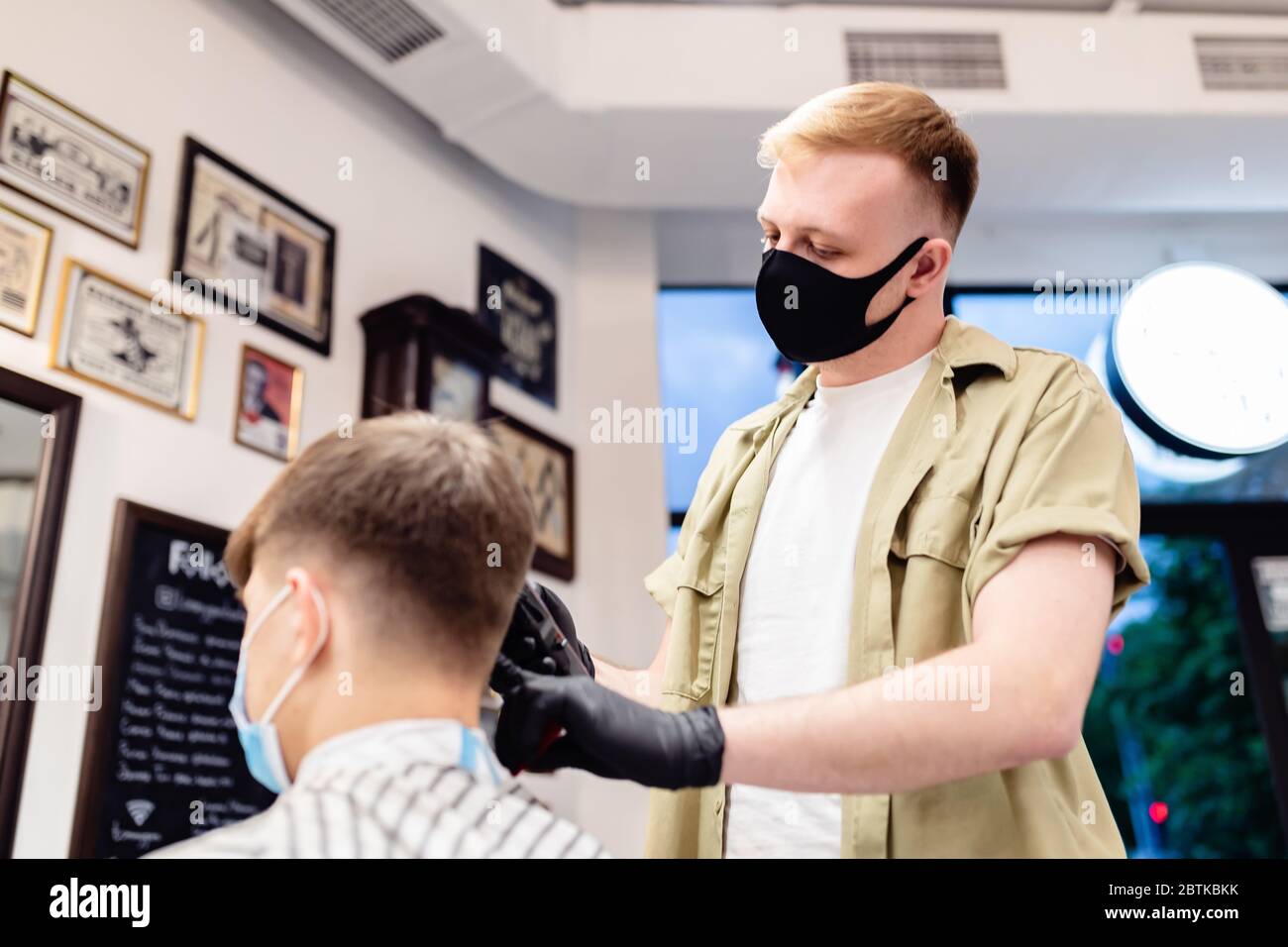 Men's haircut in a barbershop. Client and barber in anti-virus masks ...