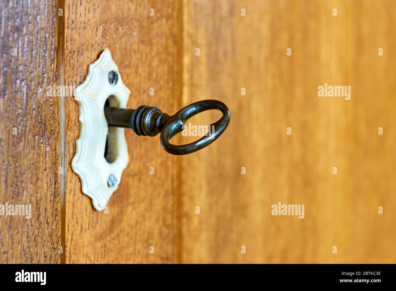 Closeup of a black key inside a keyhole of an old antique wooden closet ...
