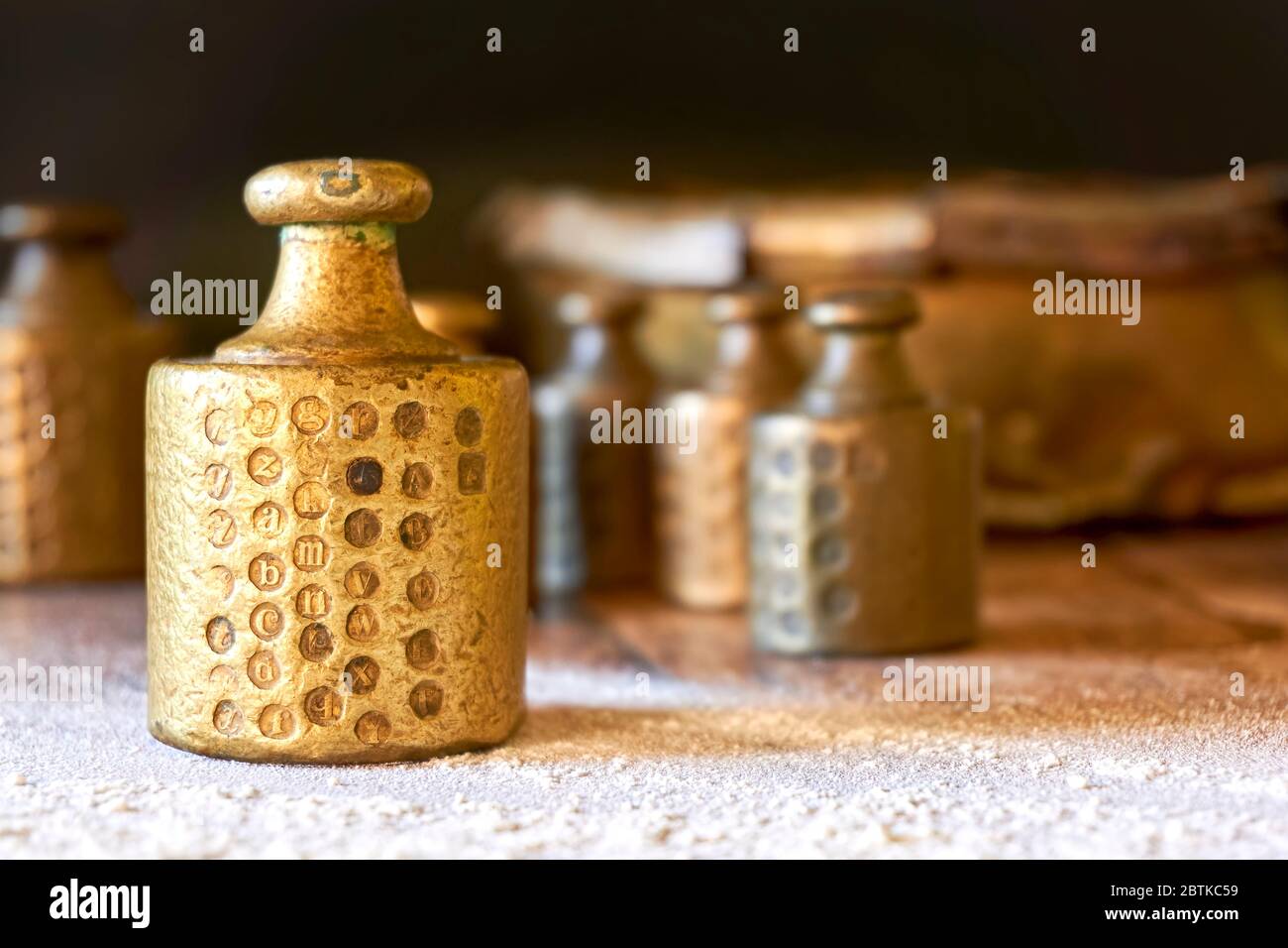 Old copper brass scale weights with calibration marks on wooden table ...
