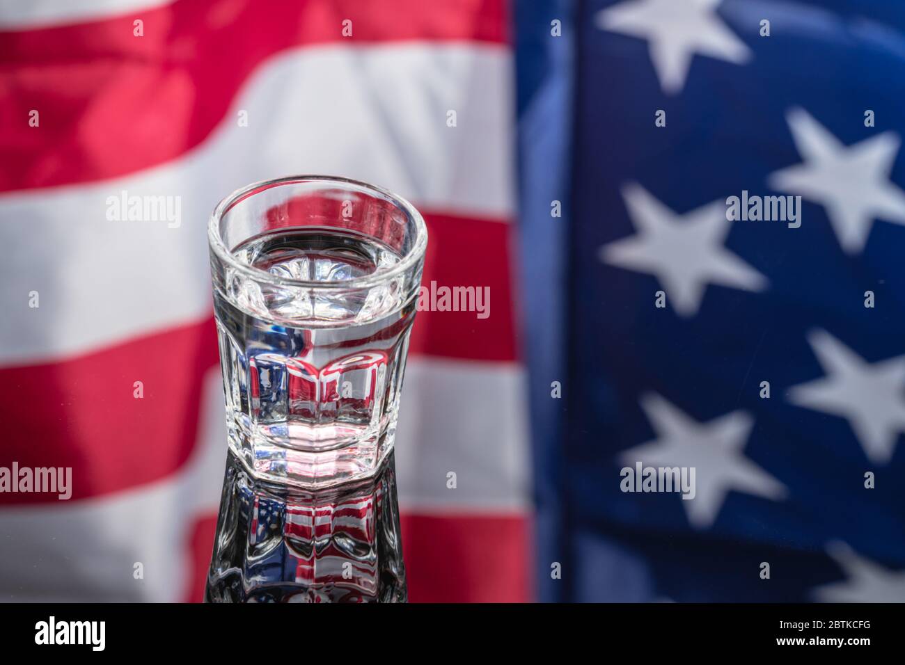 Vodka in shot glass on mirror background with American flag reflected ...