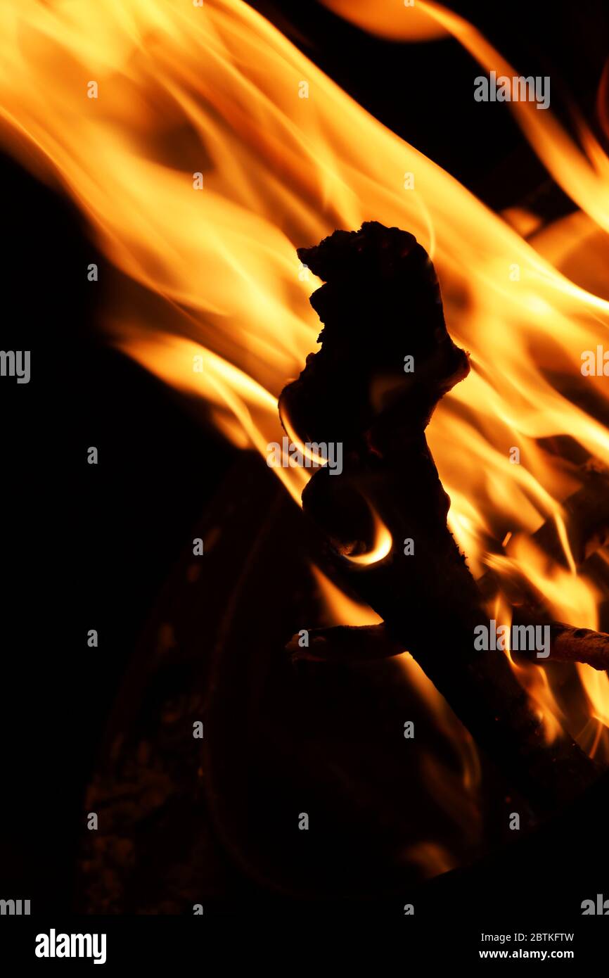 A fire pit burning wood on a cold night, flames dancing around making ...