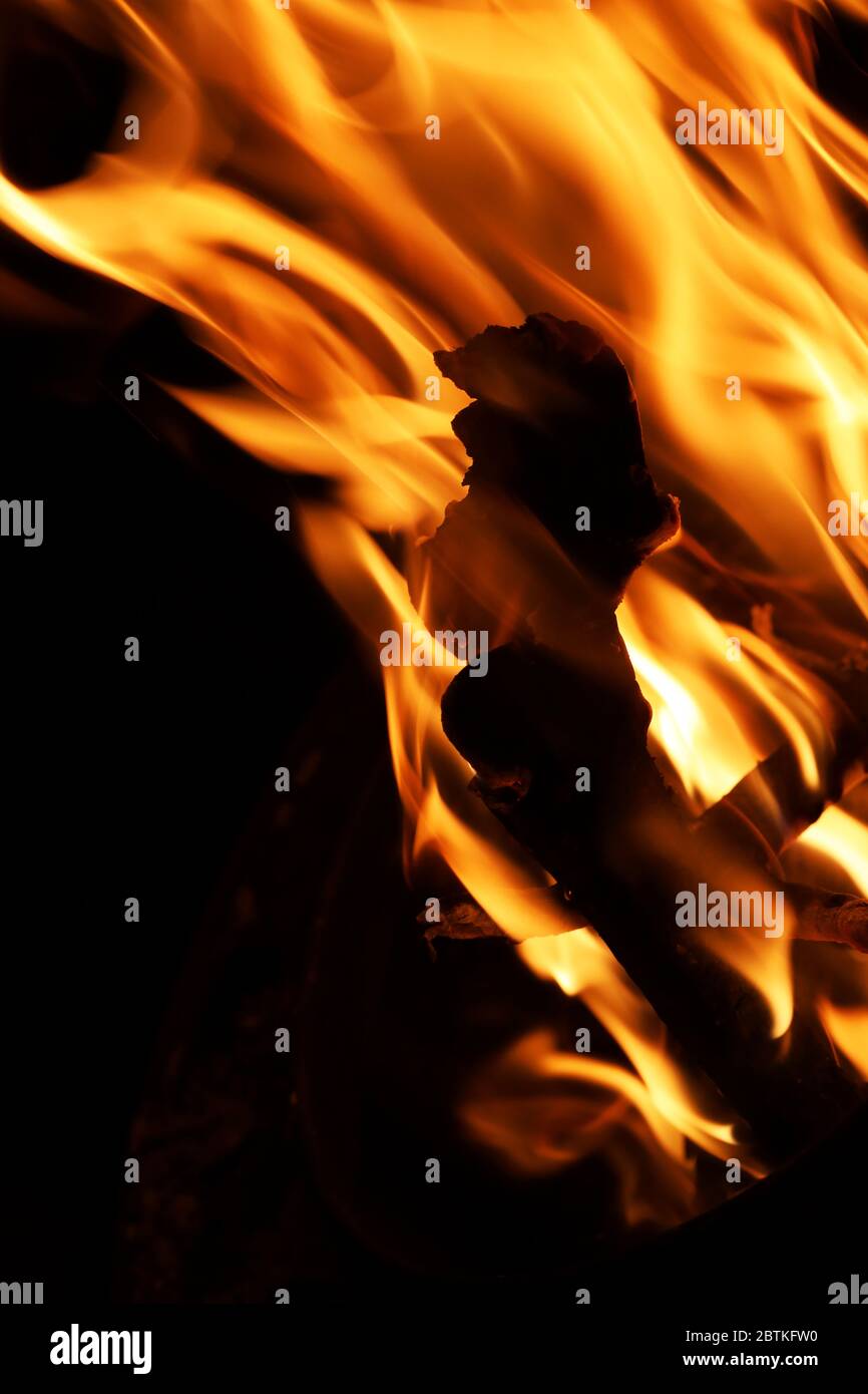A fire pit burning wood on a cold night, flames dancing around making ...