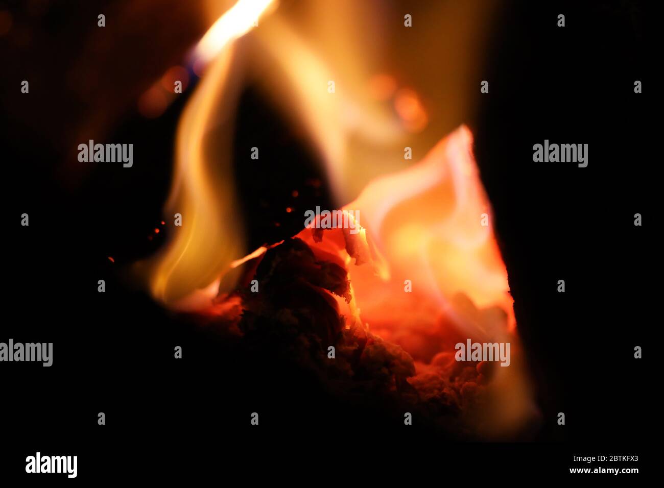 A fire pit burning wood on a cold night, flames dancing around making ...