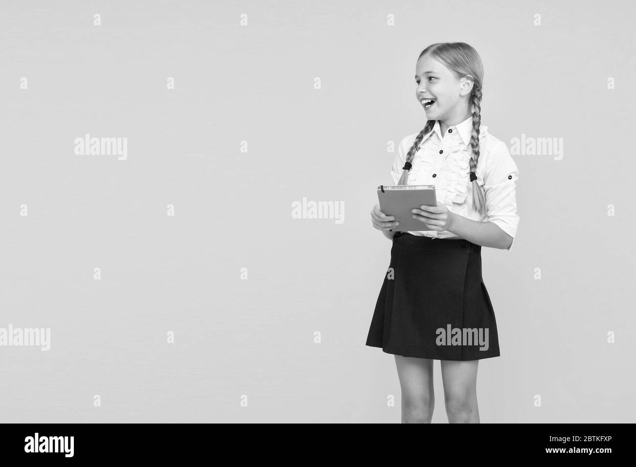 The joy of good knowledge. Cute small girl holding book on yellow ...