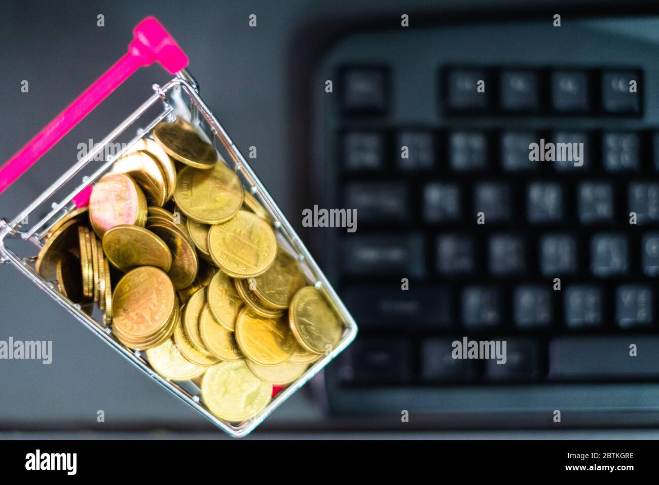 Coins in supermarket cart trolley with computer and keyboard for online ...