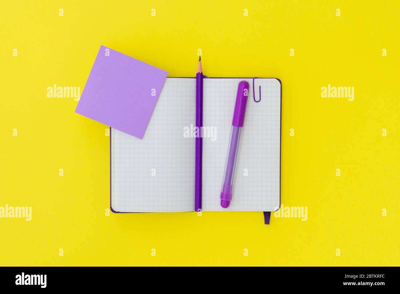 Purple notepad, pencil and marker on a yellow background. Copy space ...