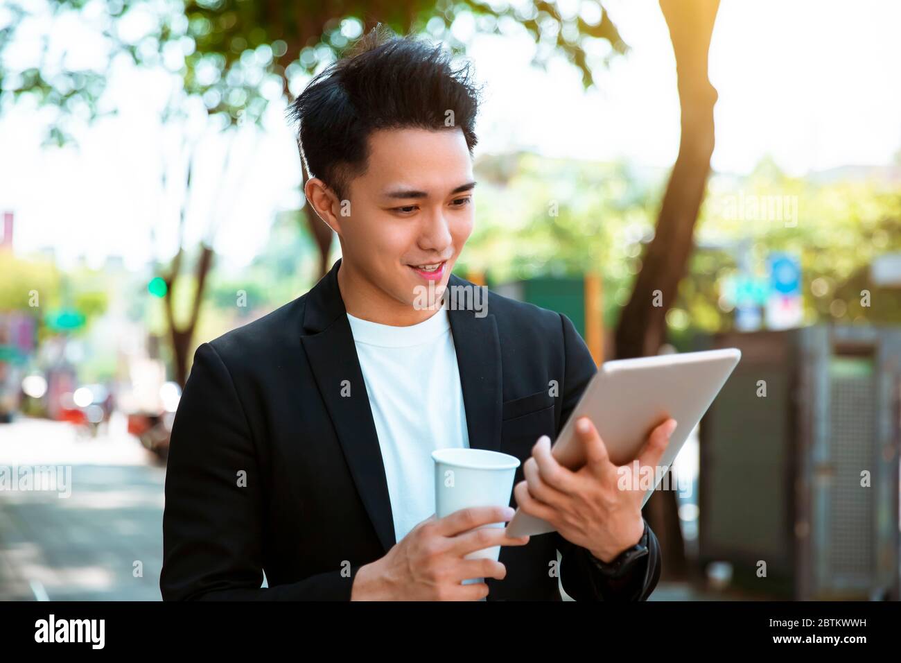 Business man with tablet walking on street Stock Photo - Alamy