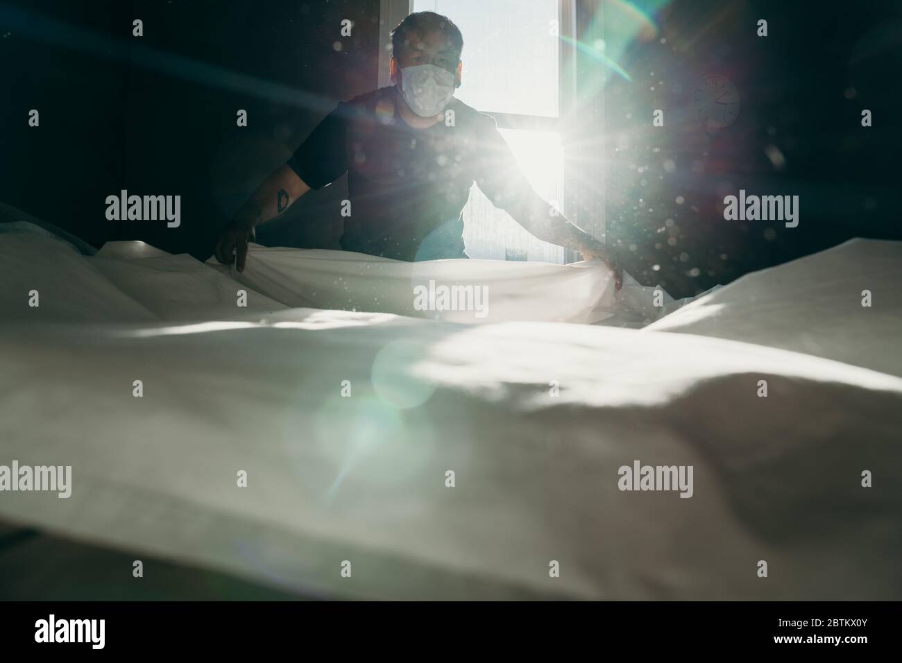 Asian man cleaning bed in morning. House keeping action. Bedroom gainst ...