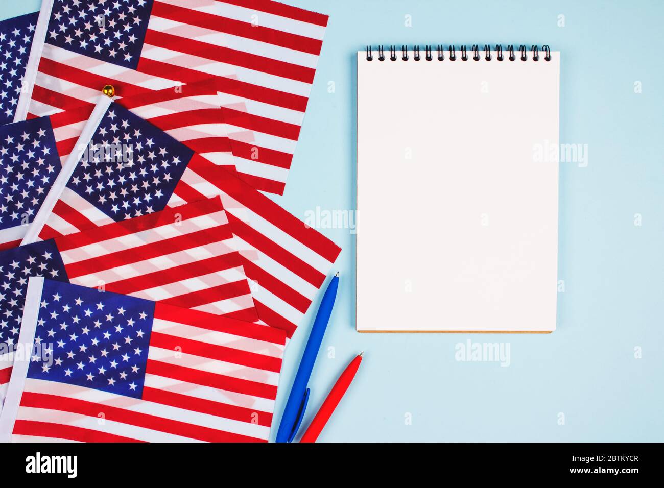 Top view on set of american flags, red and blue pens and empty notebook ...