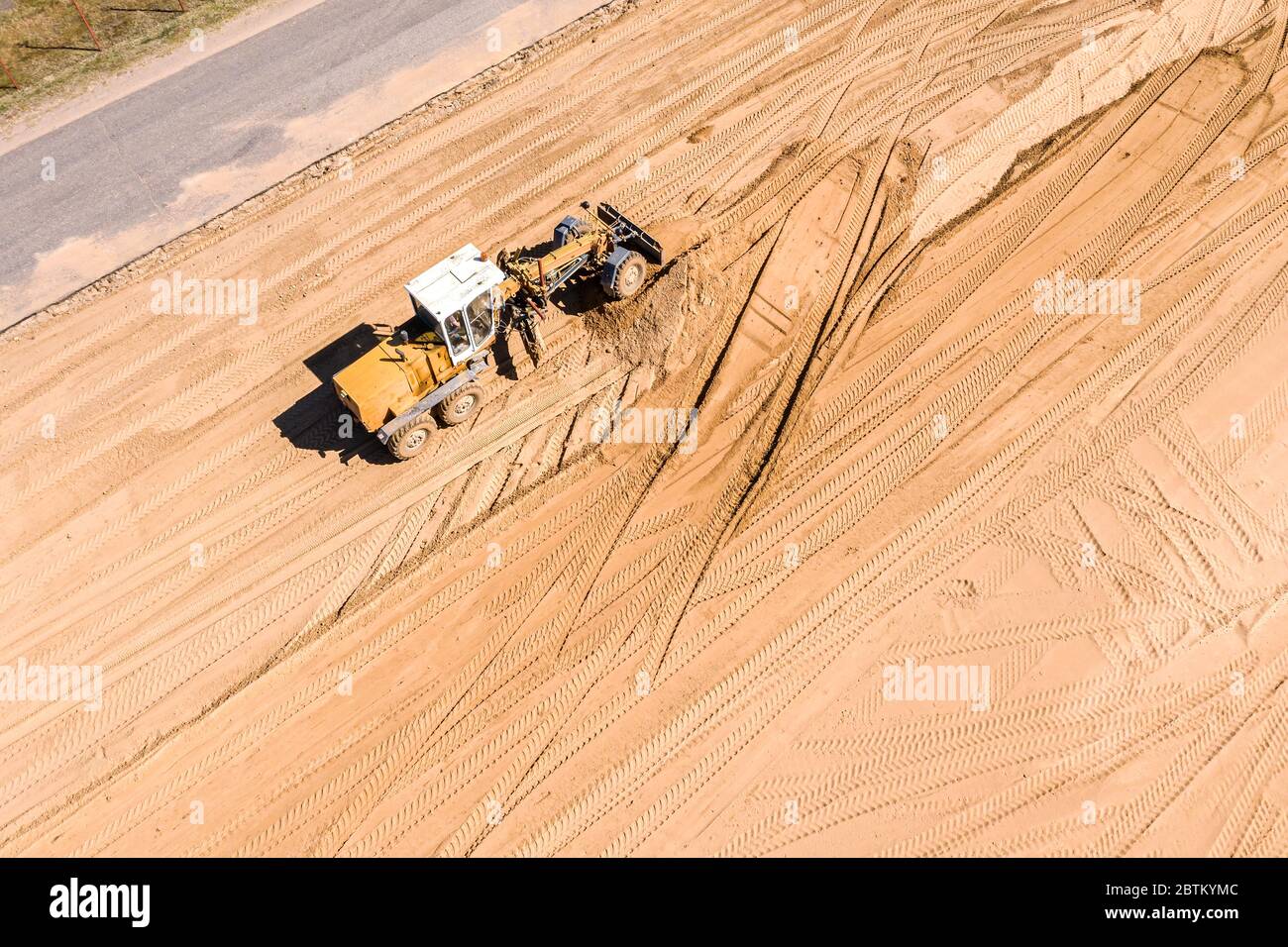 road construction site with heavy machinery. yellow grader levels the ...