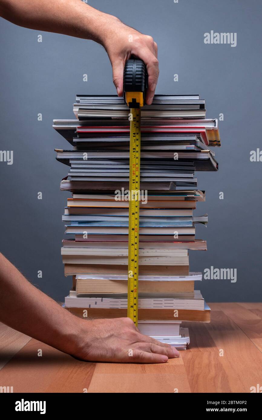 Hands of a person measuring the size of a mountain of books ...