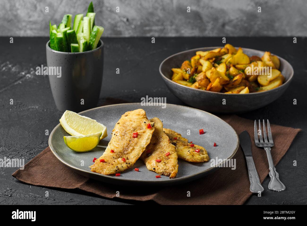 Fried breaded hake fillet with spice and roasted potato wedges Stock ...