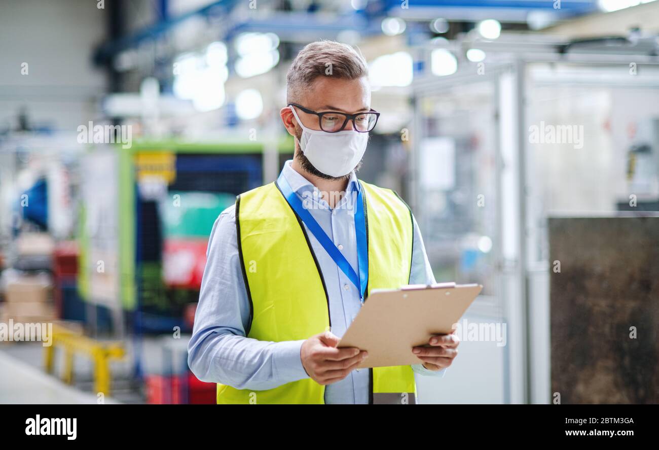 Technician or engineer with protective mask working in industrial ...