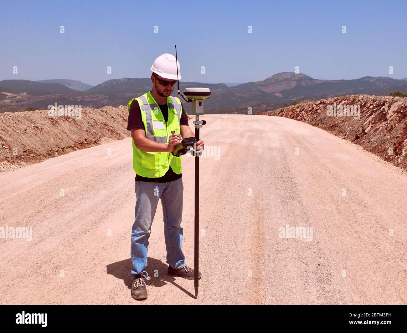 Geodetic engineer surveyor in white hard hat doing measurements with ...