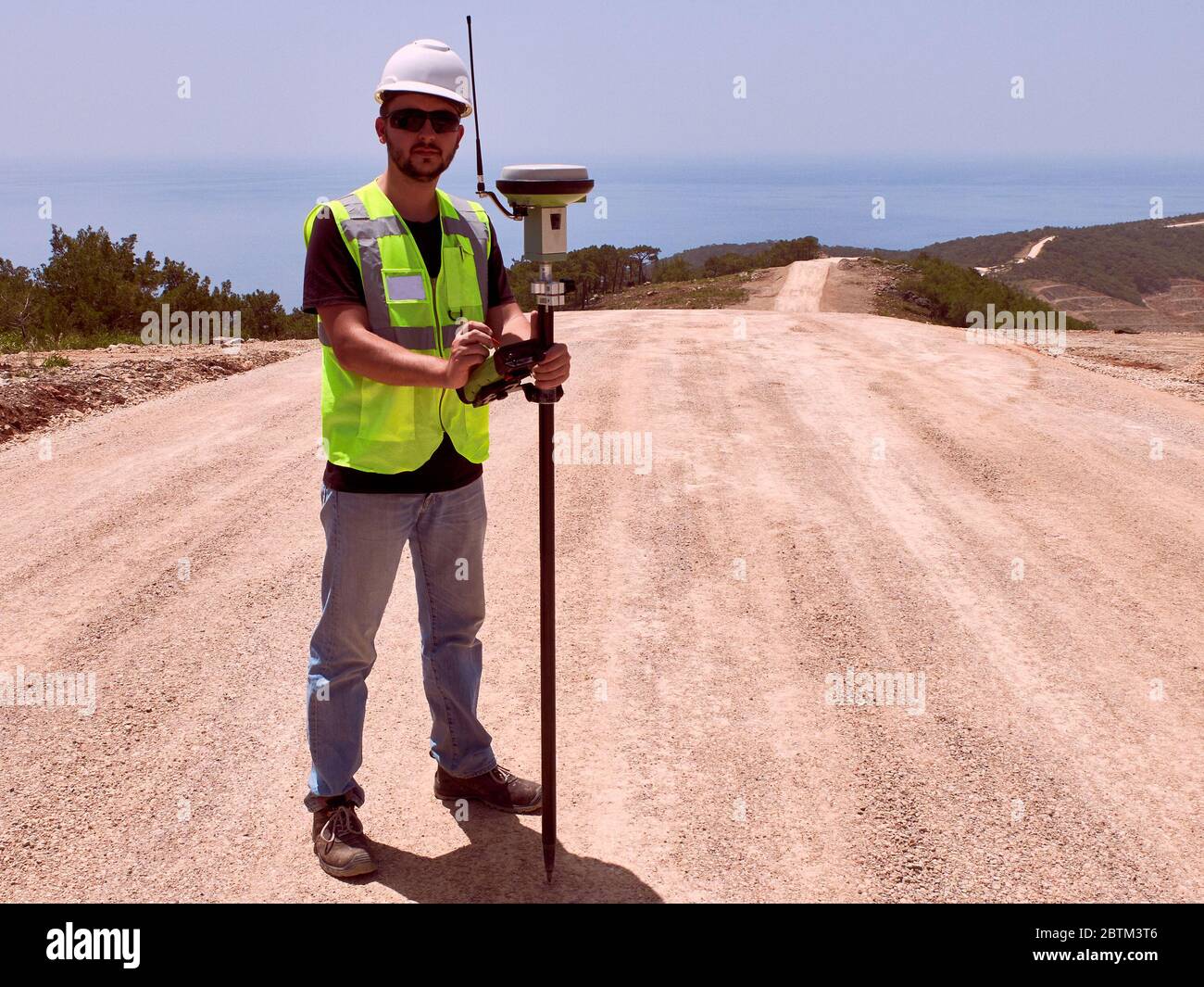 Geodetic engineer surveyor in white hard hat doing measurements with ...