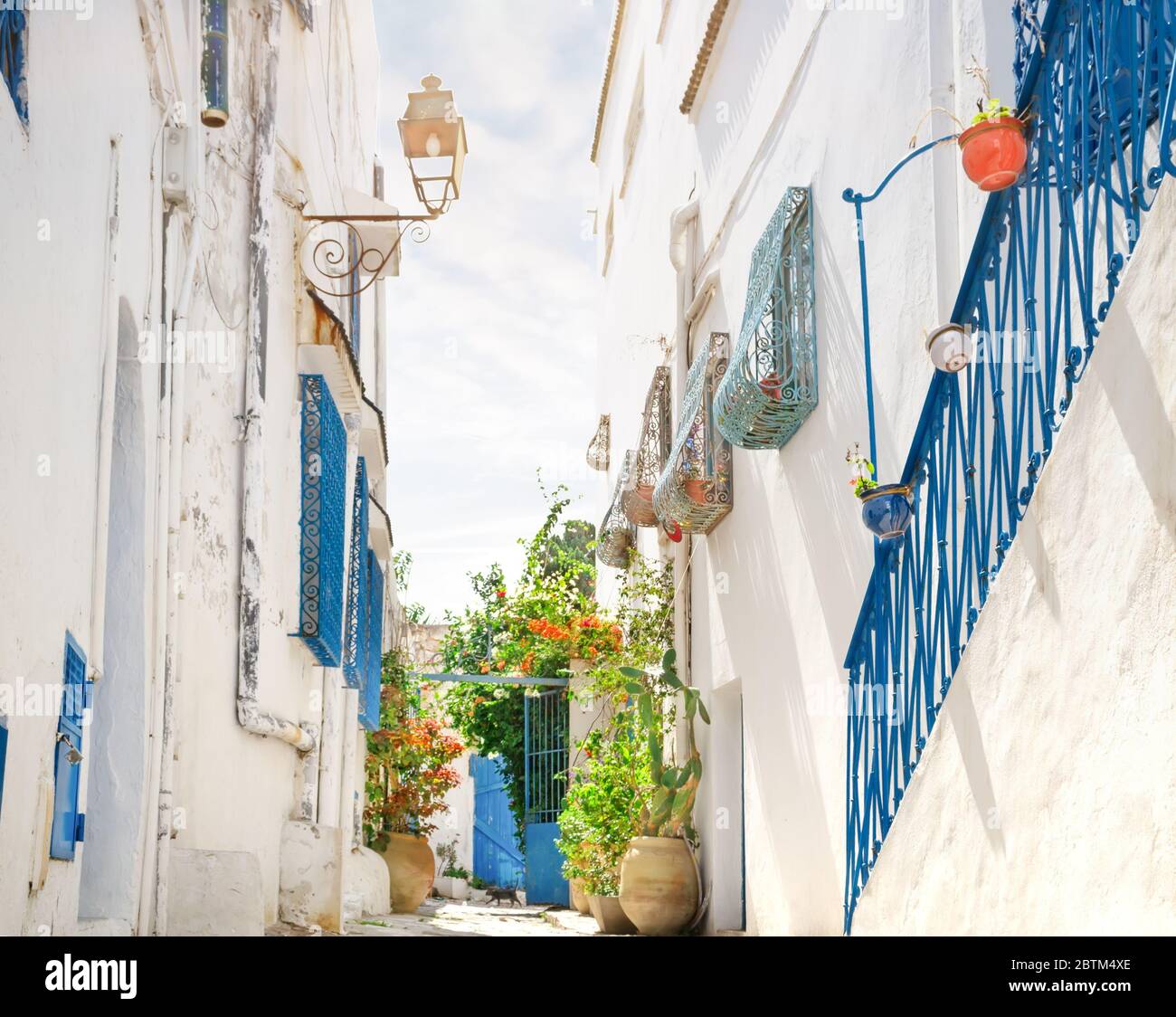 Street with white and blue houses under bright sun Stock Photo - Alamy