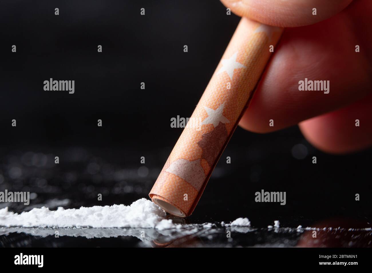 Cocaine line being snorted by a man with a rolled bill. Close up shot ...