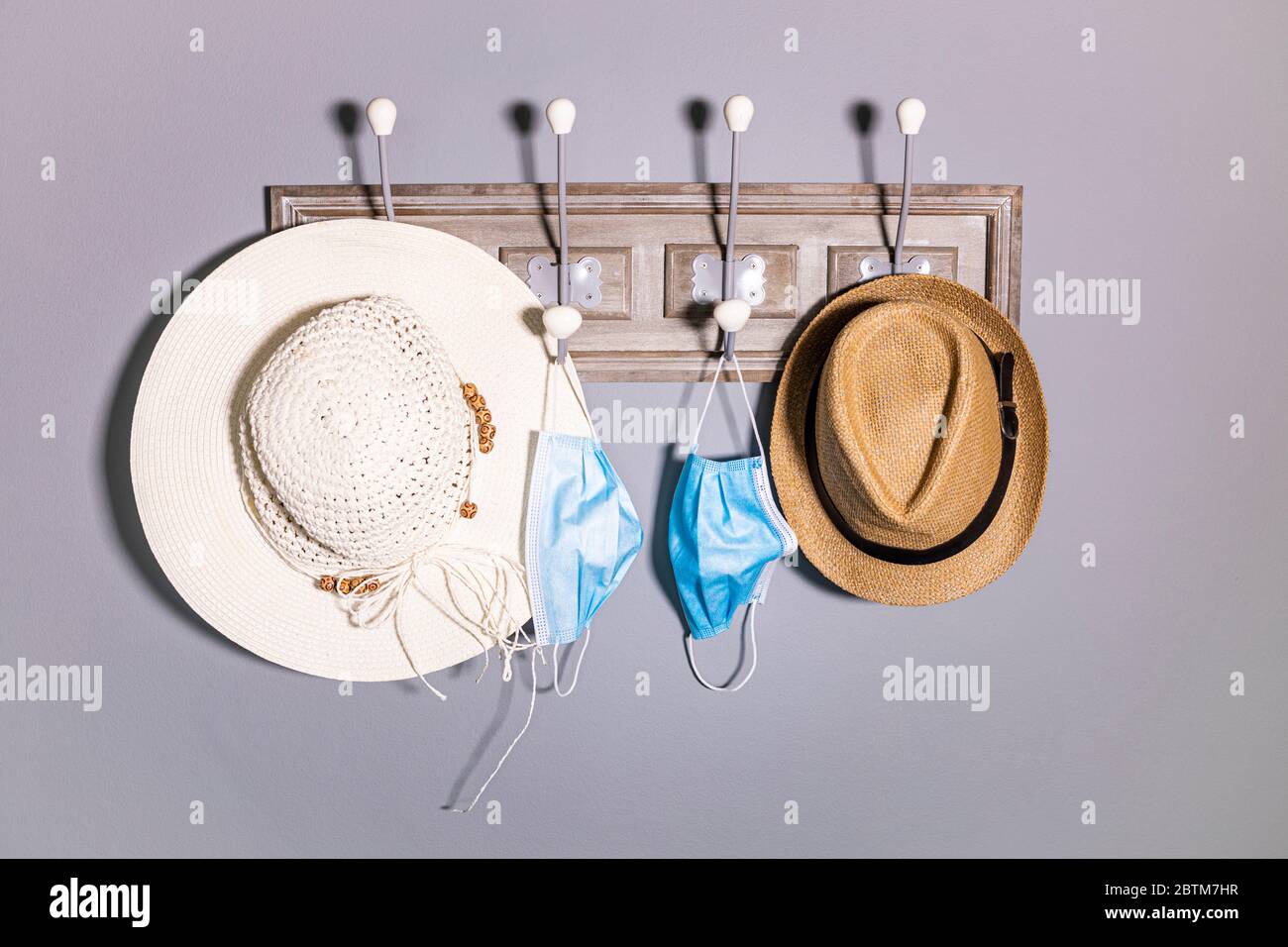 Coat rack with a hats and a pair of safety masks Stock Photo - Alamy