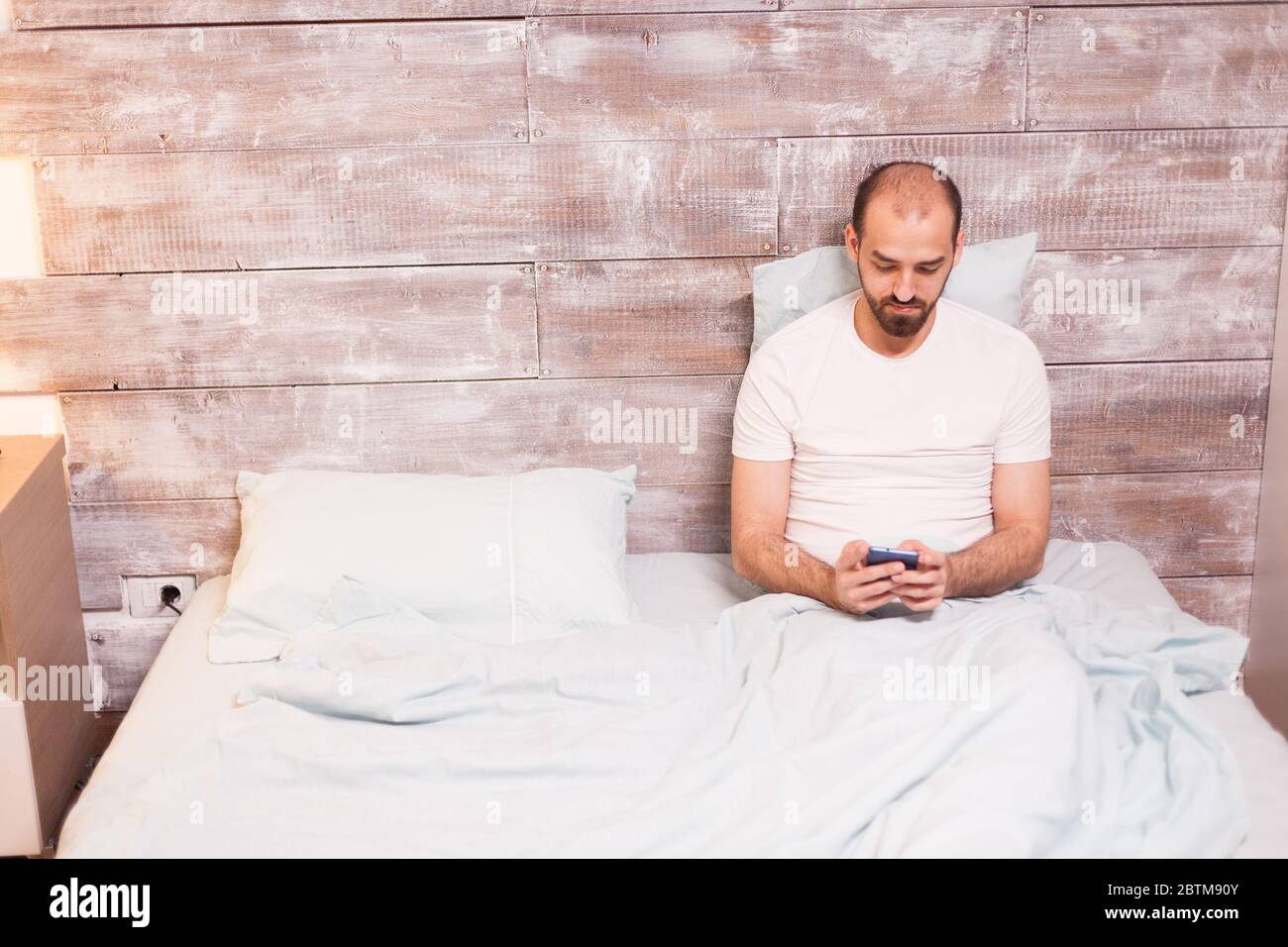 Relaxed man at night using his mobile phone laying in bed Stock Photo ...
