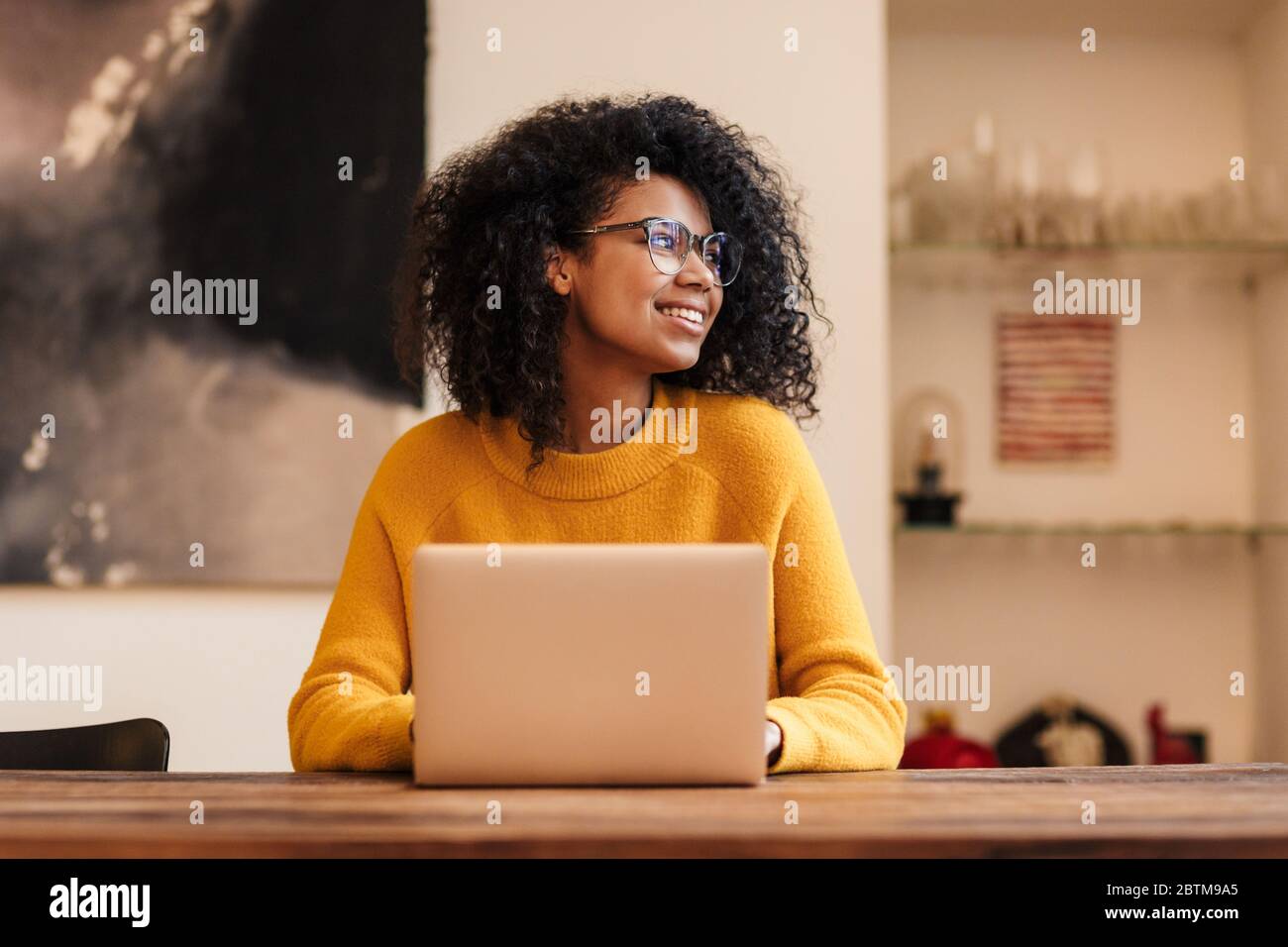 Image of cheerful african american woman in eyeglasses using laptop ...