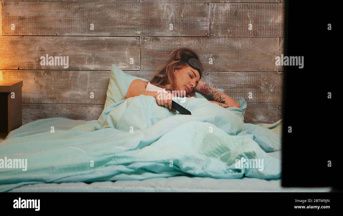 Beautiful young woman in pajamas falling asleep while watching tv Stock ...