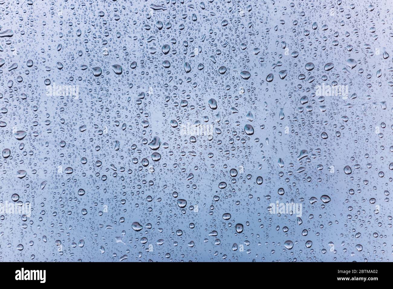 Blue water drops on colored window background. Raindrop on the window ...