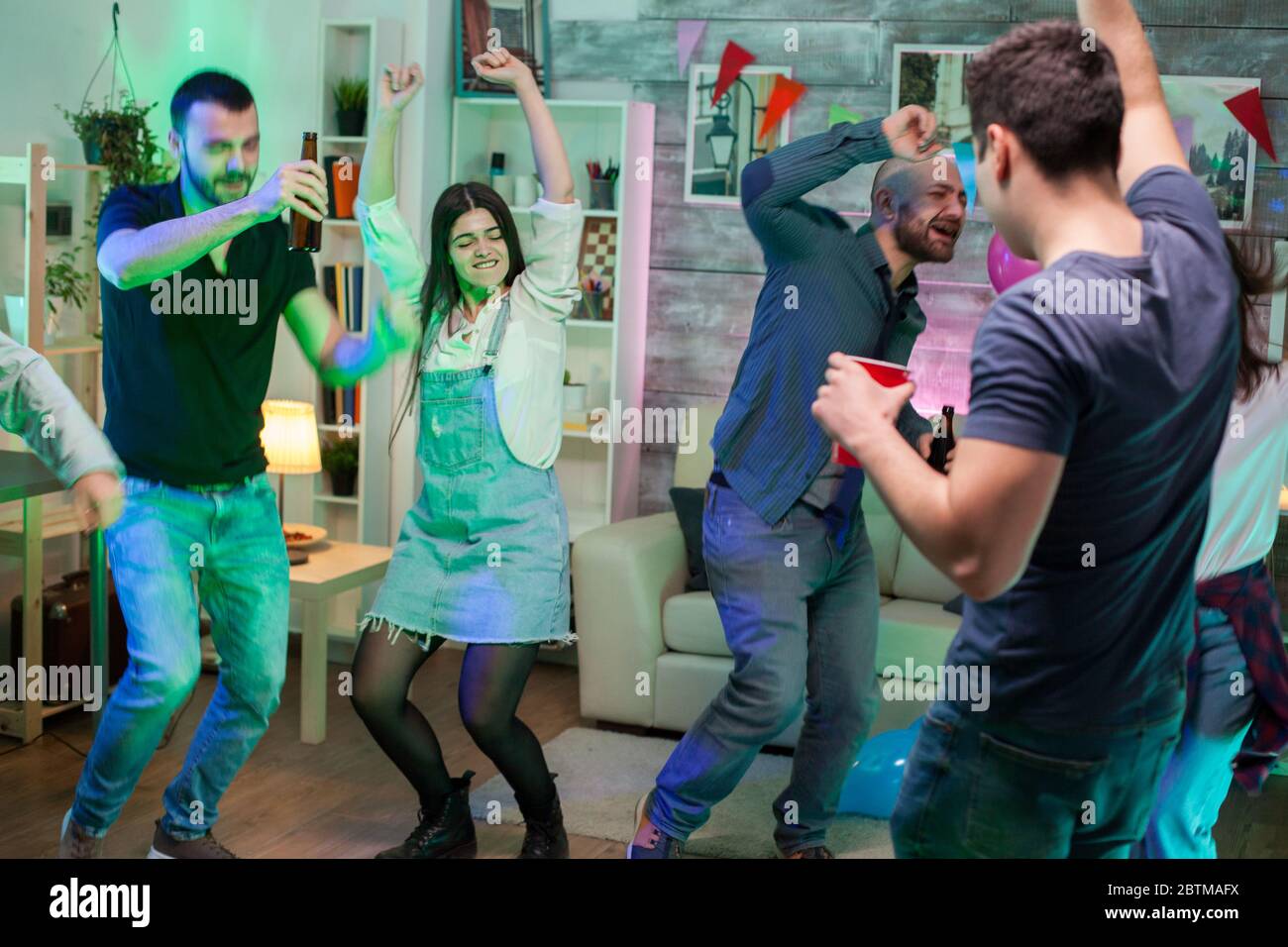 Excited group of friends dancing at a disco party to celebrate the ...