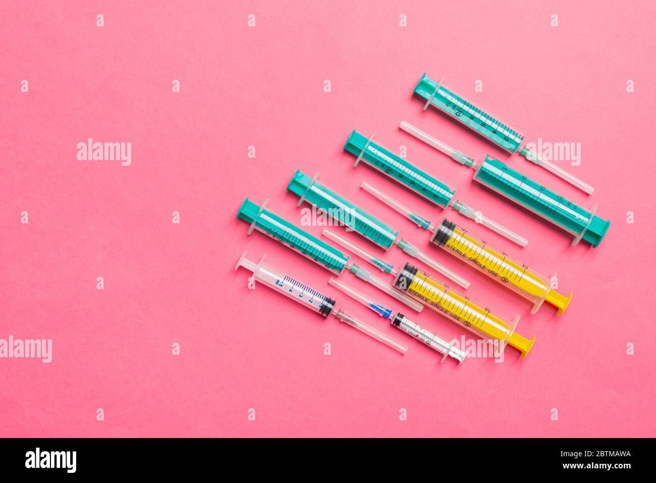 Top view of medical syringes with needles at pink background with copy ...