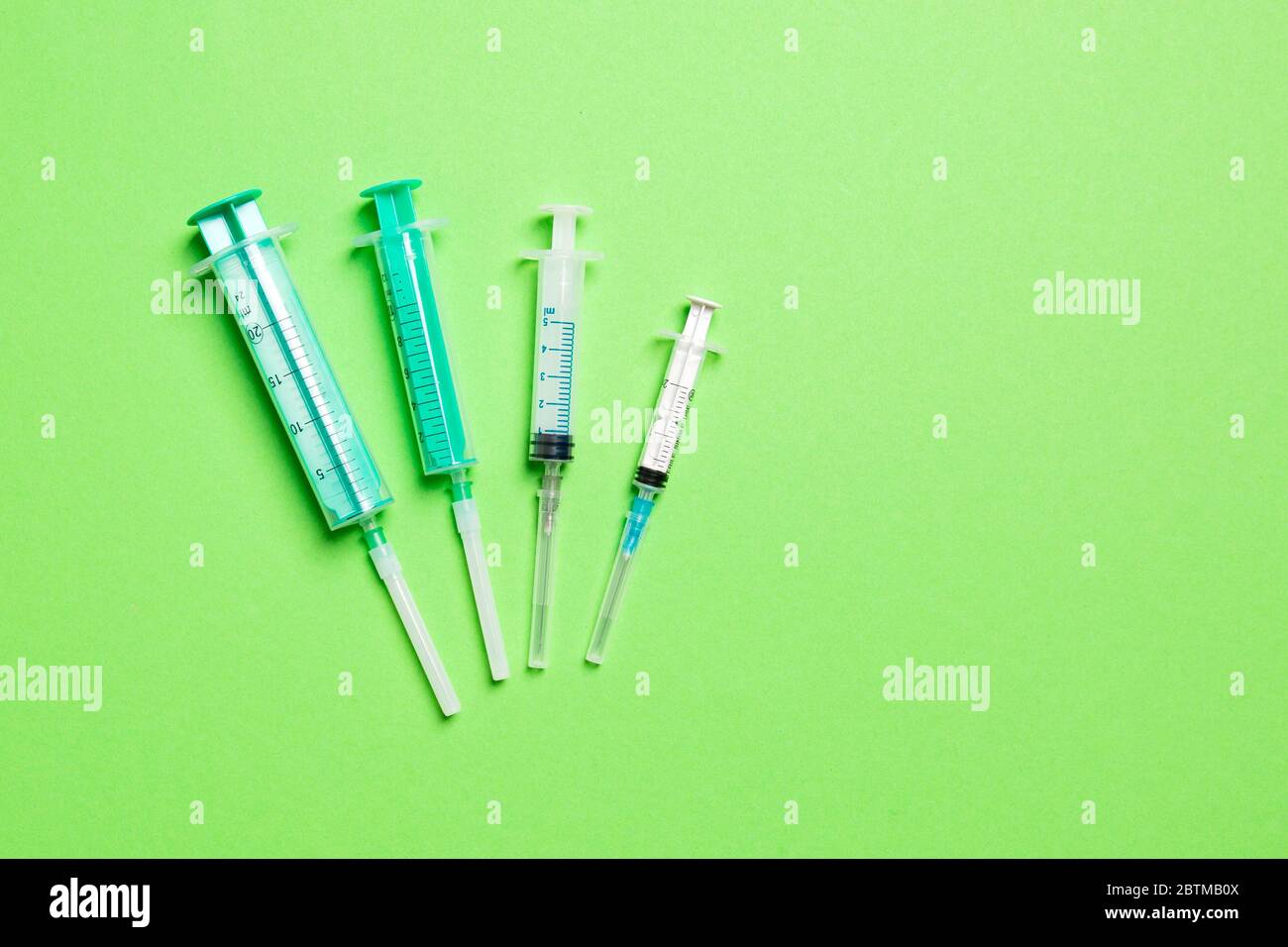 Top view of different syringes at green background. Medical injection ...