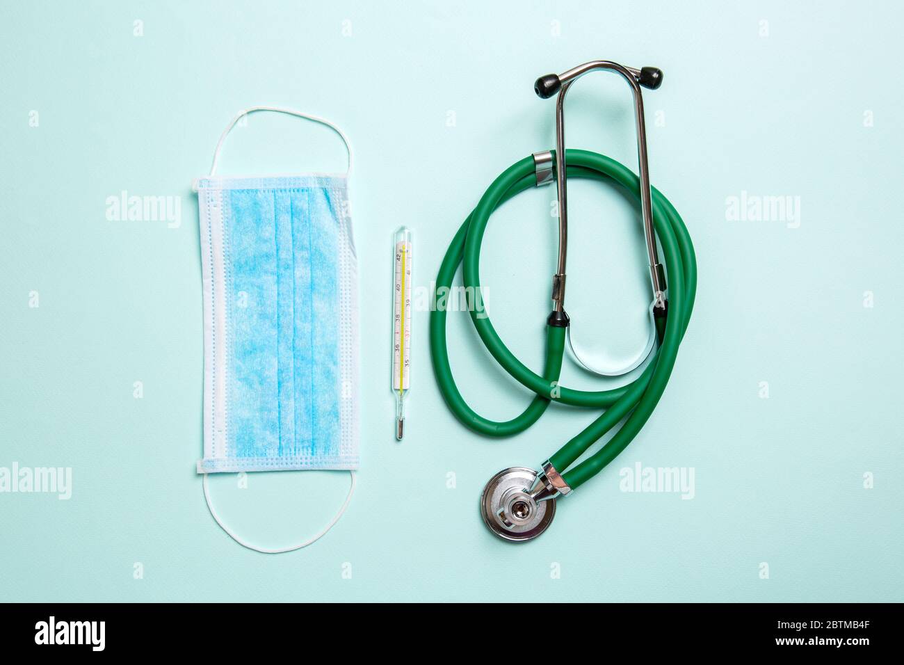 Top view of stethoscope, mercury thermometer and a protective face mask ...