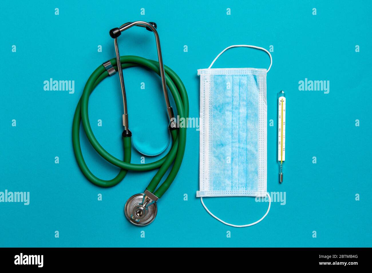 Top view of stethoscope, mercury thermometer and a protective face mask ...