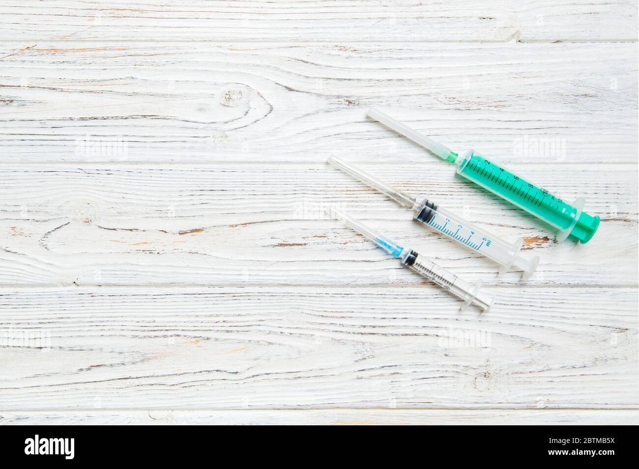 Top view of syringes of different sizes on wooden background. Medical ...