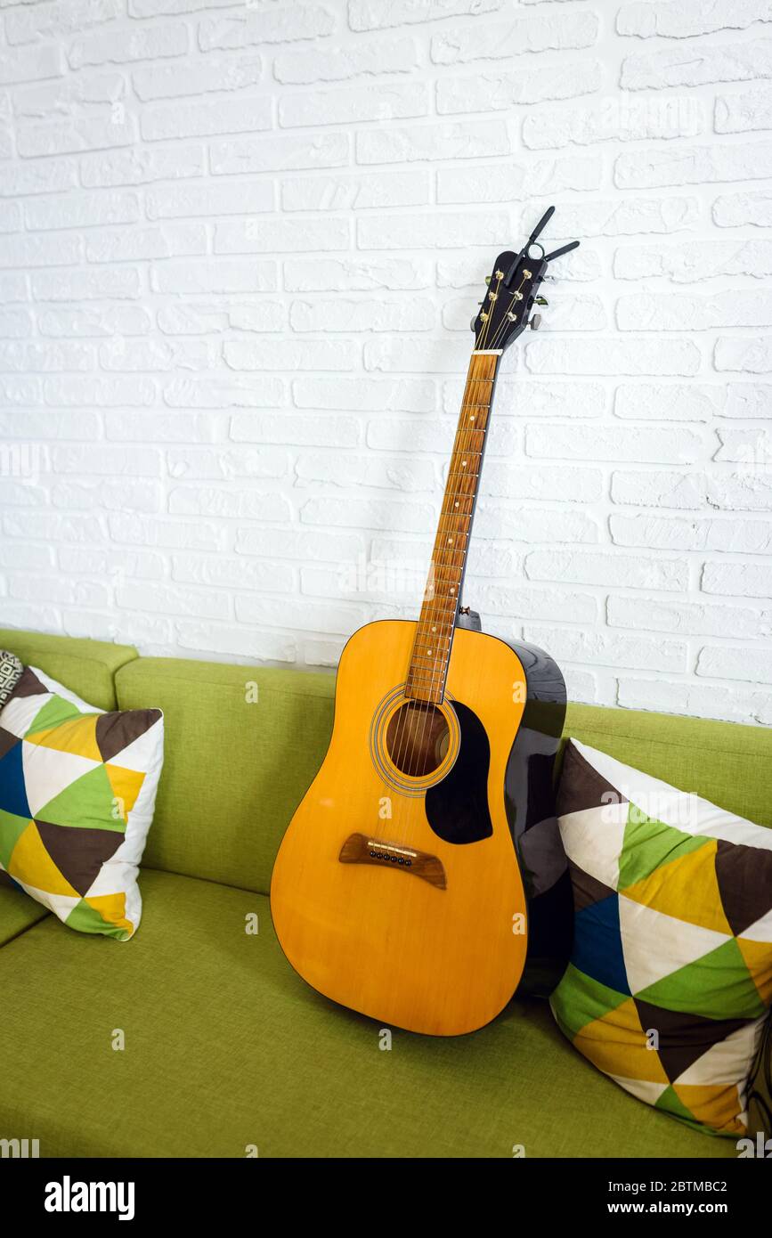 Acoustic guitar on a green sofa. Cozy living room interior Stock Photo ...