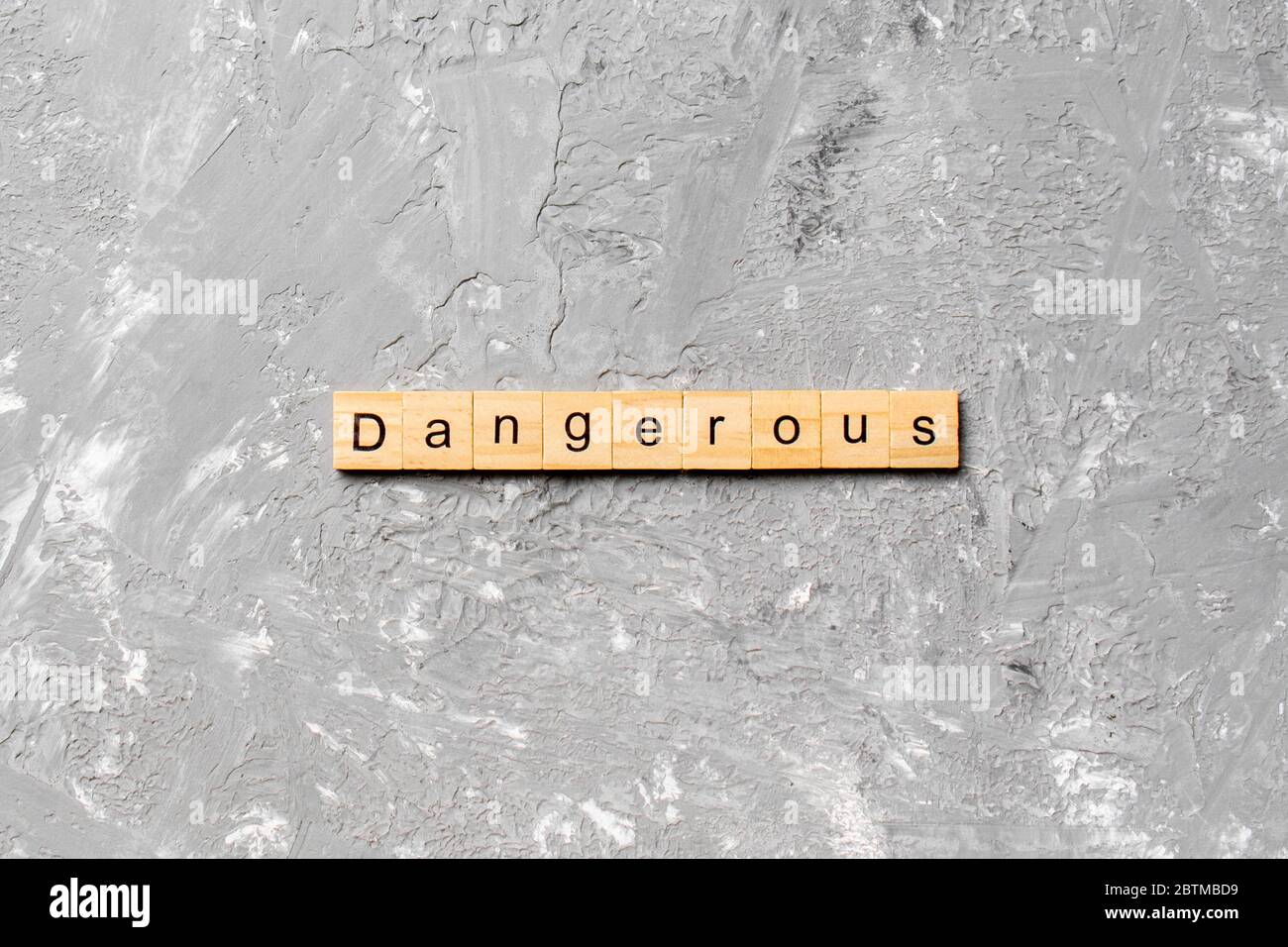 dangerous word written on wood block. dangerous text on cement table ...