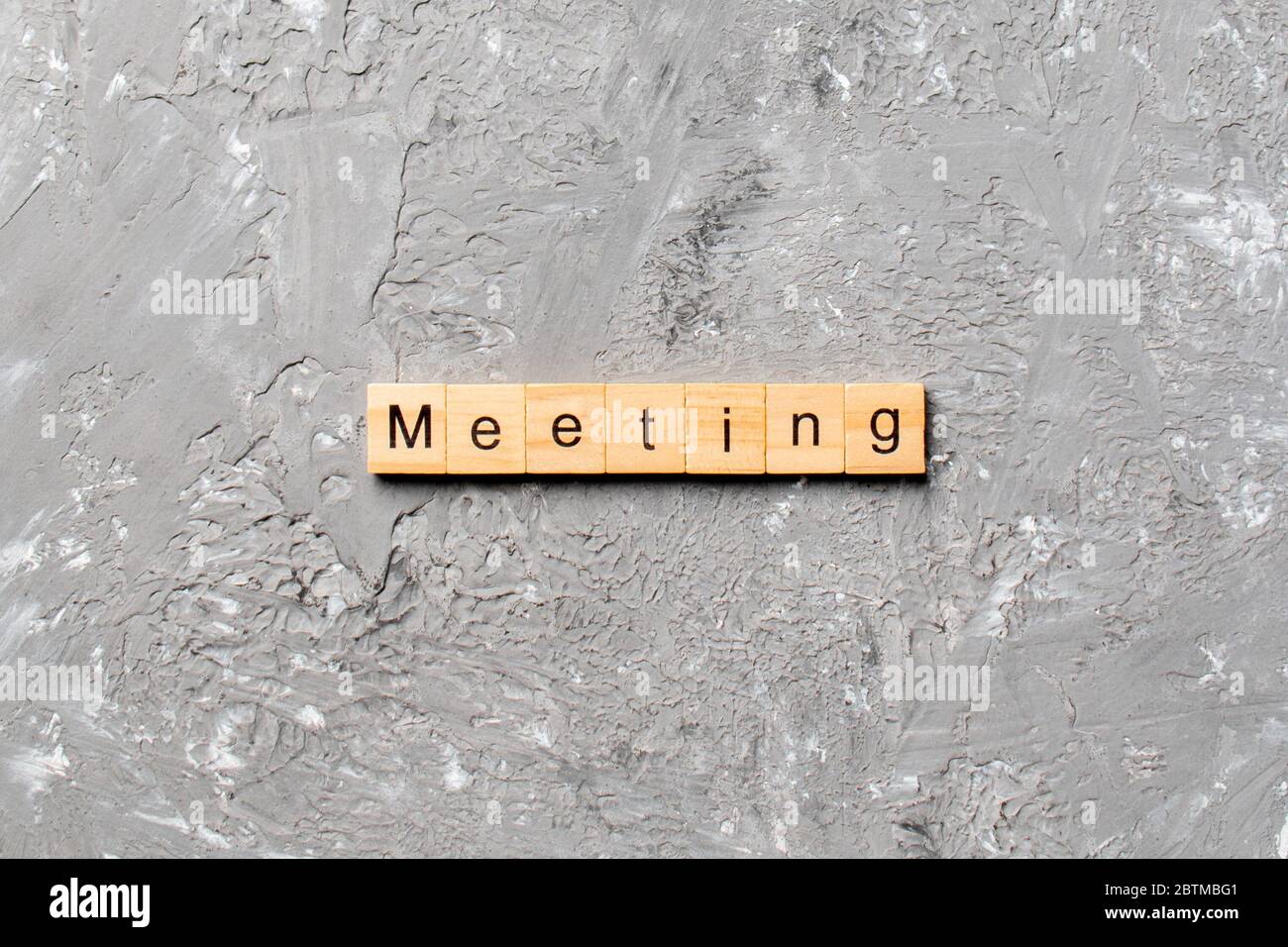 MEETING word written on wood block. MEETING text on cement table for ...