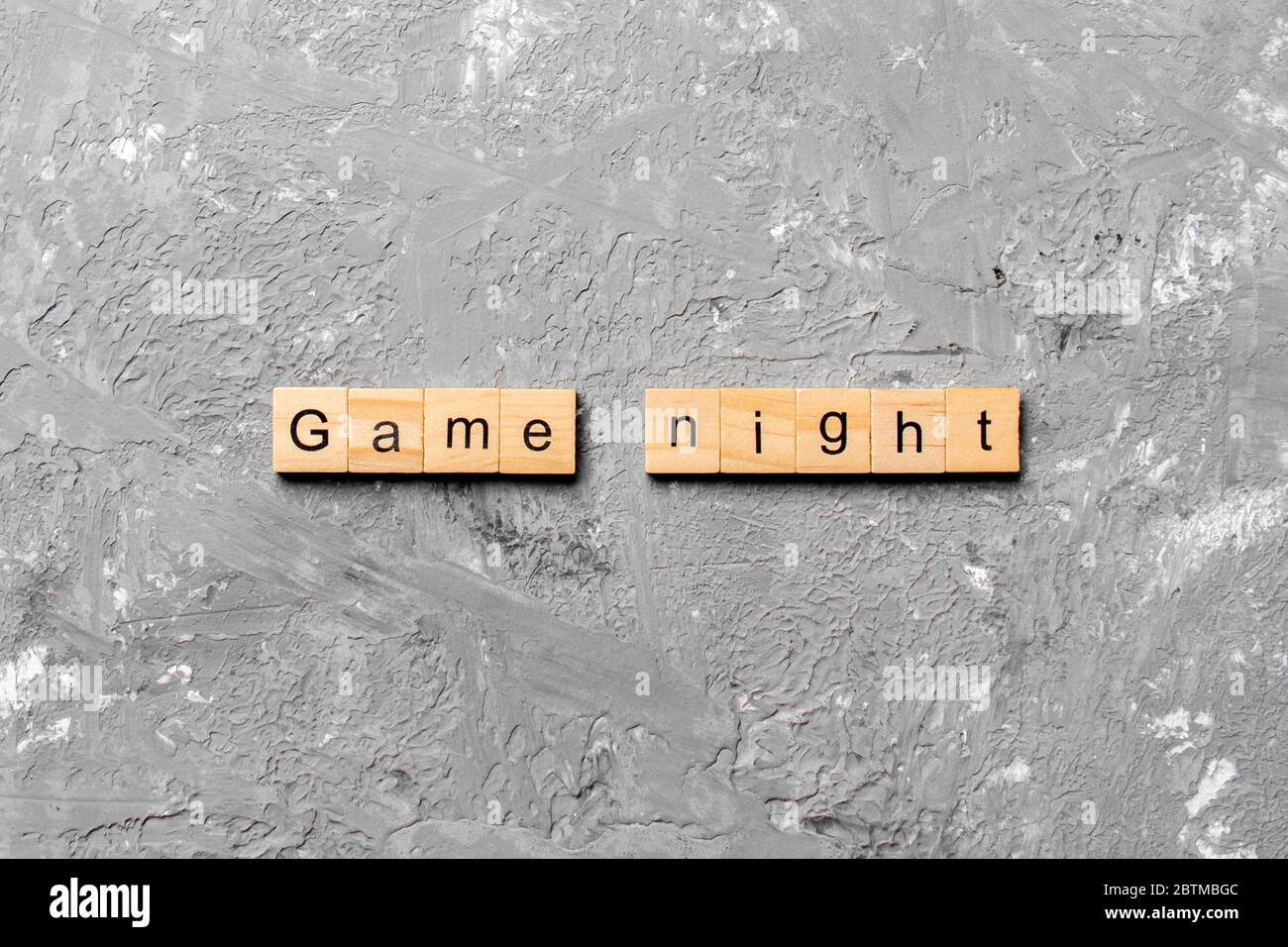 Game Night word written on wood block. Game Night text on cement table ...