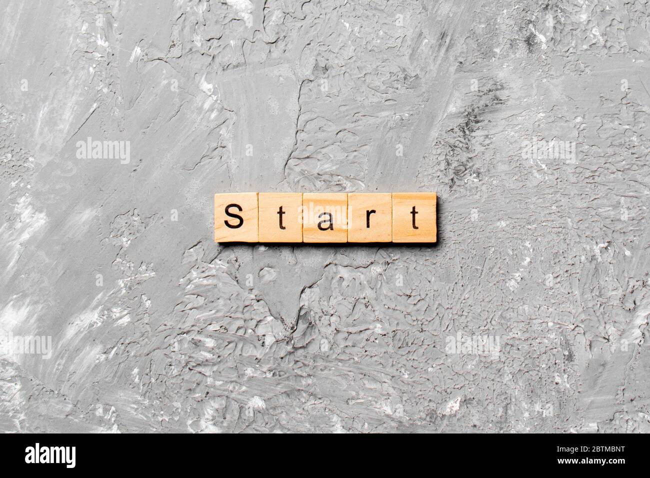 Start word written on wood block. Start text on cement table for your ...