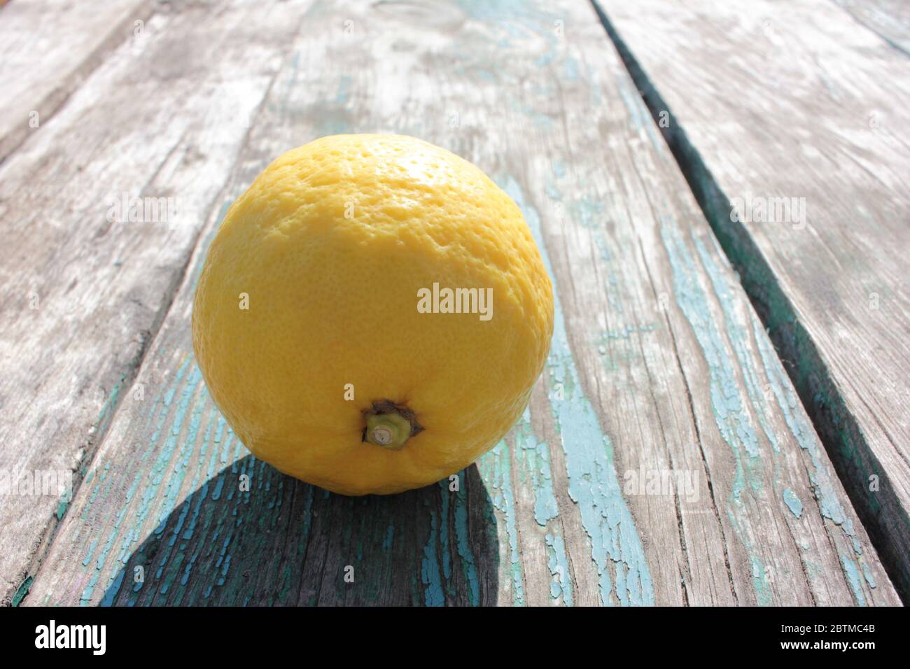Whole single lemon fruit on rough wooden background in sunny day Stock ...
