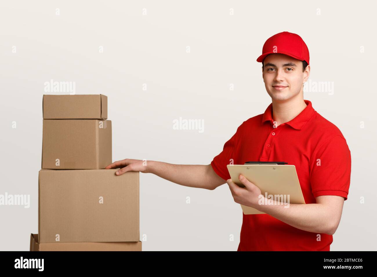 Shipping concept. Deliveryman in red uniform checks parcels in ...