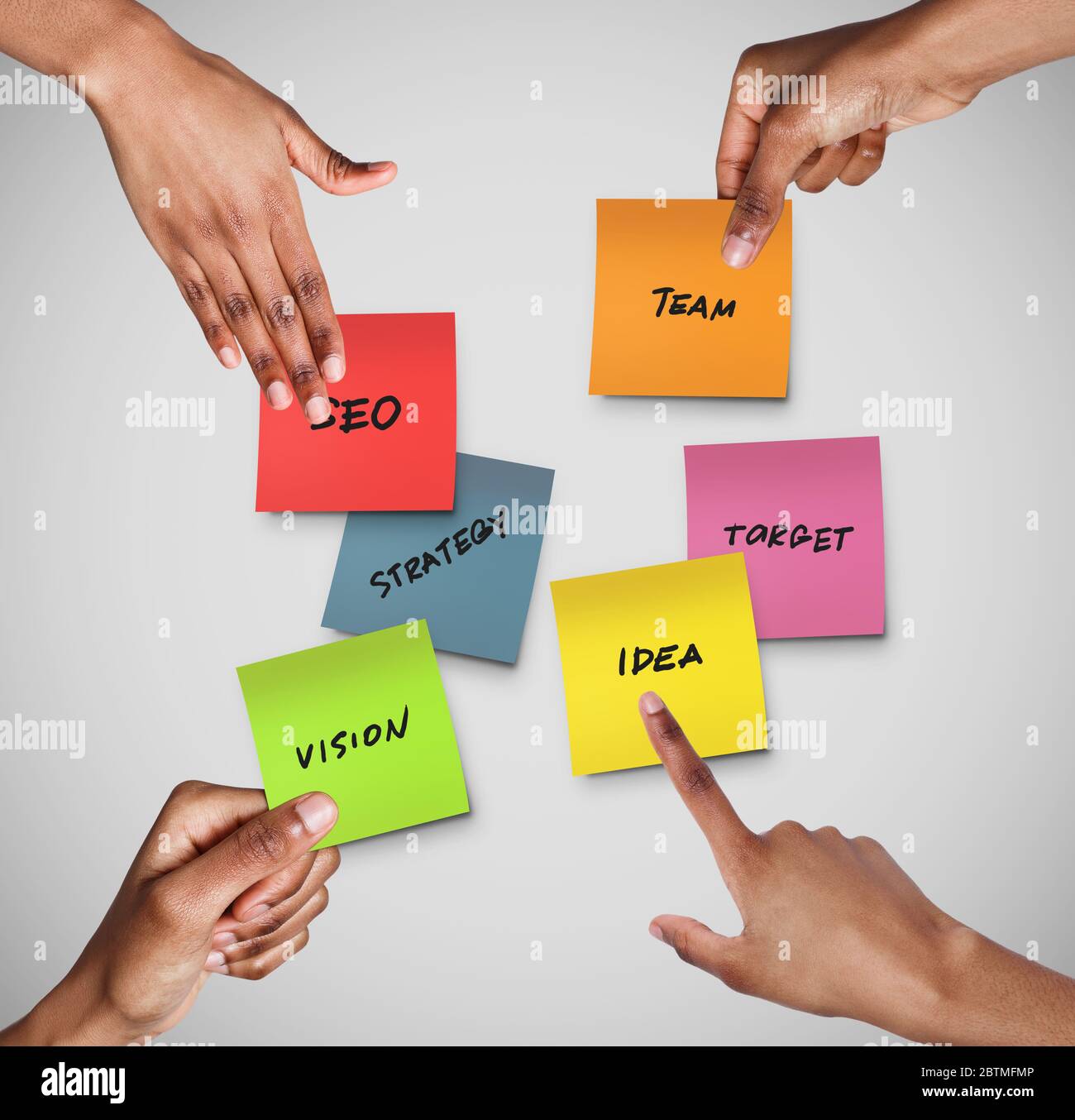 People's hands reaching for notes with various business related words ...