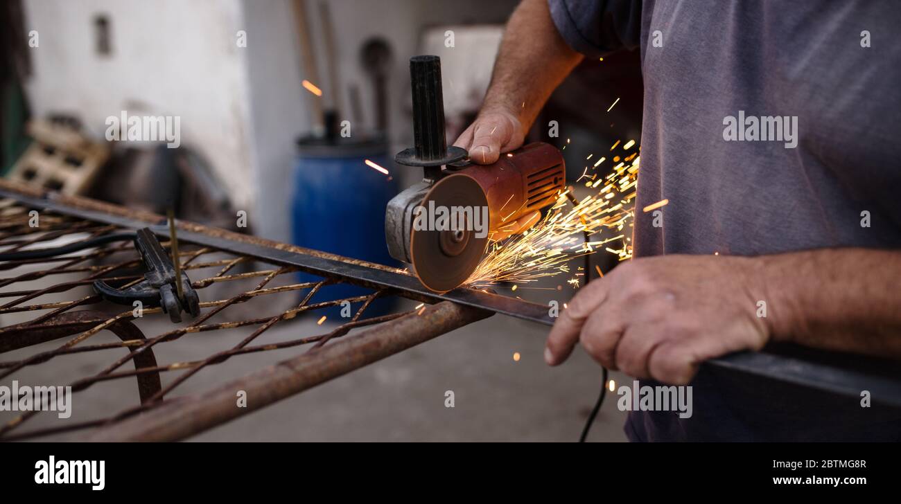 Industrial worker cutting and welding metal with many sharp sparks ...