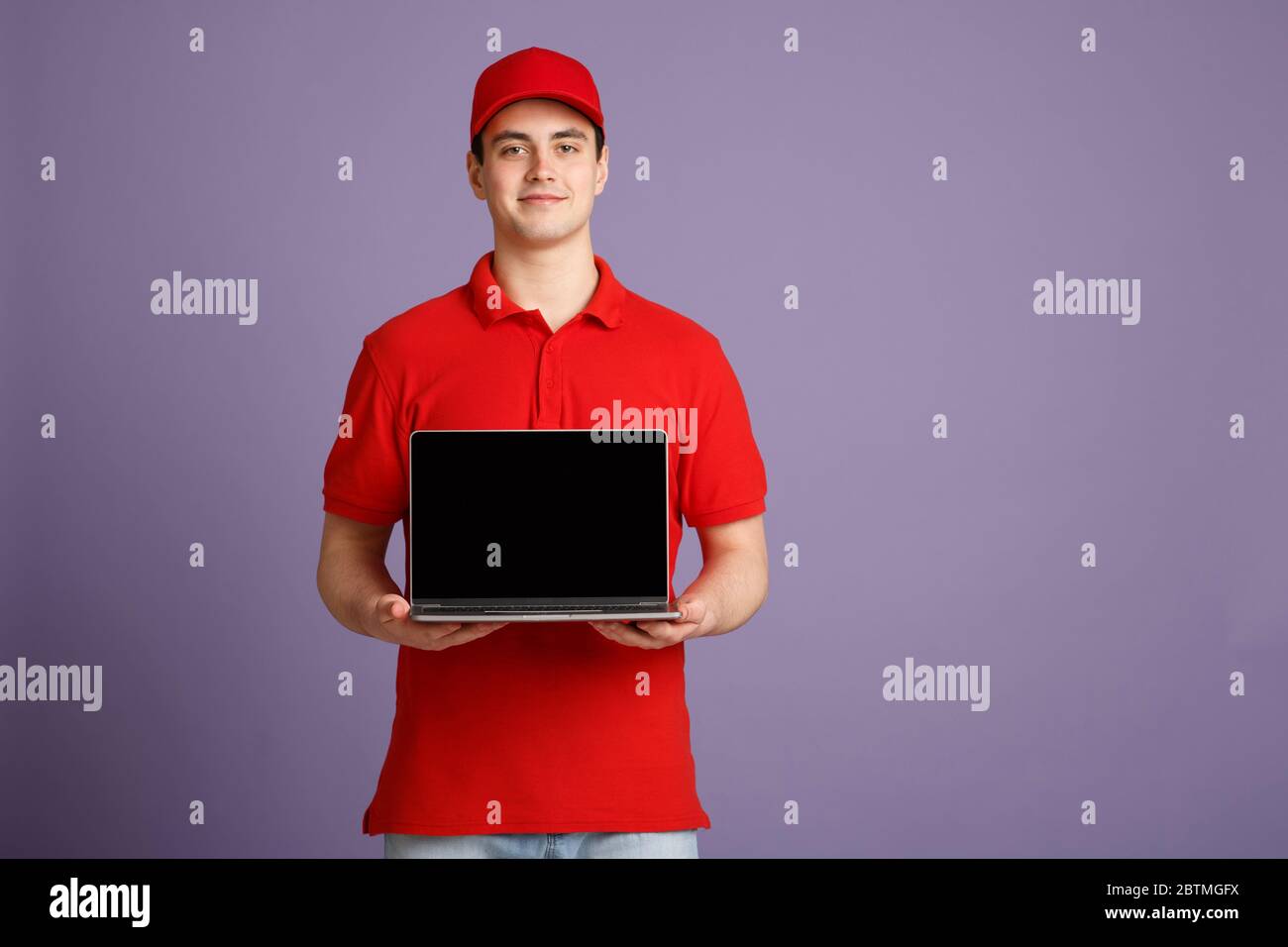 Track package online. Delivery man holding laptop with blank screen ...